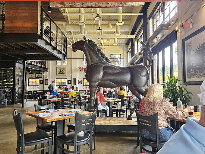 Diners enjoy the restaurant's soaring ceilings and industrial-meets-warm ambiance, with the iconic horse sculpture standing sentinel over memorable meals.