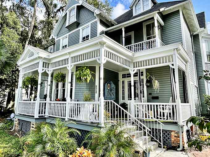 Relax on the spacious white porch of this charming, historic inn, surrounded by lush greenery and a warm, inviting atmosphere.