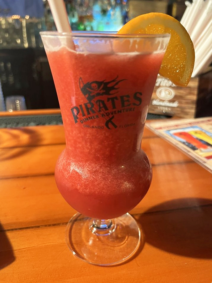 The signature Pirates Dinner Adventure cocktail glows like a tropical sunset, garnished with orange and promising rum-soaked merriment.