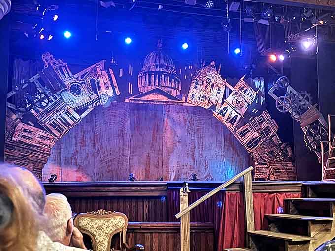 Elaborate set design creates a cityscape backdrop, proving community theater can deliver Broadway-worthy visual impact in intimate historic settings.