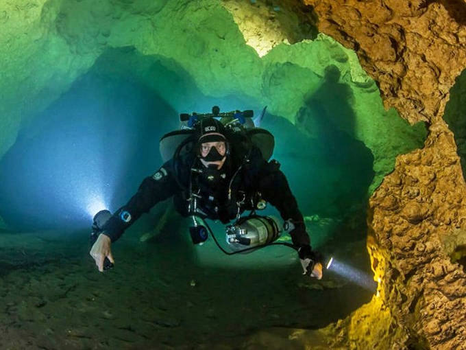 Orange Grove Sink appears as a mysterious green portal in the forest floor, its waters hiding entrances to miles of underwater caves.