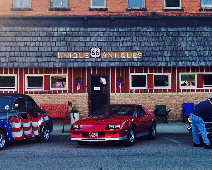 The iconic red and blue facade of 66 Unique Antiques welcomes treasure hunters with vintage cars often parked outside, creating an impromptu classic car show.