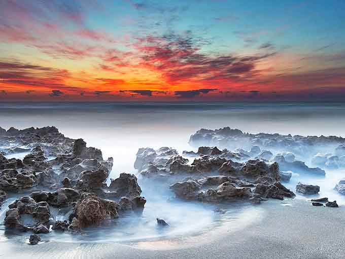 Sunset transforms Blowing Rocks Preserve into nature's masterpiece, where ancient limestone meets crashing waves in a display that outshines any man-made spectacle.