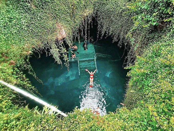Devil's Den: A swimmer floats in ethereal blue waters beneath a natural skylight, where sunbeams create nature's most spectacular light show.