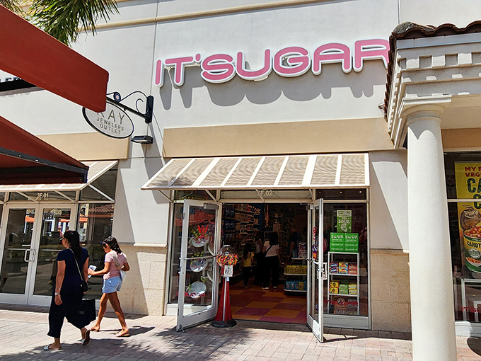 Exterior: The glowing pink IT'SUGAR sign beckons candy lovers like a neon lighthouse guiding sweet-toothed sailors to sugary shores.