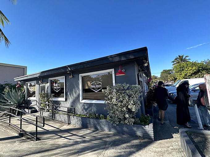 A modest gray building with a simple sign belies the culinary treasures within. The line forming outside tells the real story.
