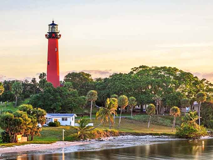 The iconic Jupiter Inlet Lighthouse stands tall against a golden sunset, its crimson tower a beacon of coastal charm that's been guiding mariners home since 1860.