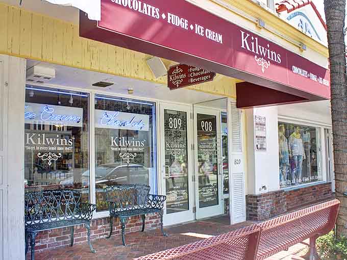The welcoming storefront of Kilwins beckons with its burgundy awning and charming brick facade – a sweet oasis on a Florida street.