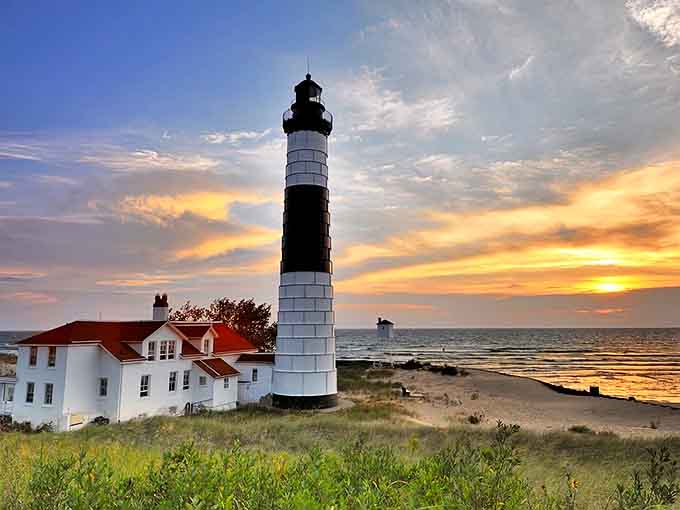 Big Sable Point Lighthouse stands tall against a fiery sunset, its black and white stripes a beacon of maritime history.