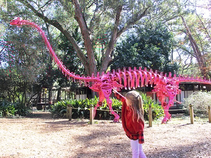 A hot pink brachiosaurus stretches toward the sky, proving that prehistoric creatures are even more impressive when they look like they've been dipped in flamingo-colored paint.