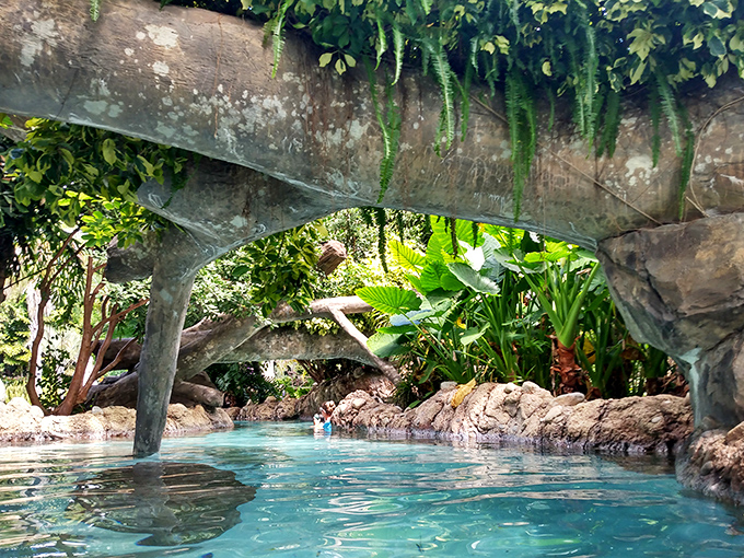 Tranquil turquoise waters flow beneath stone arches, creating a hidden grotto where adventure and relaxation perfectly merge.