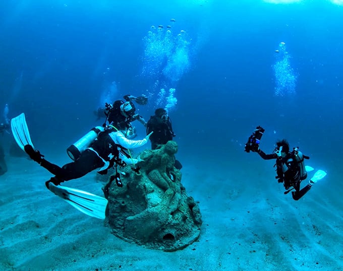 Divers explore the otherworldly terrain of the 1,000 Mermaids Reef, where art and marine conservation create an underwater paradise.