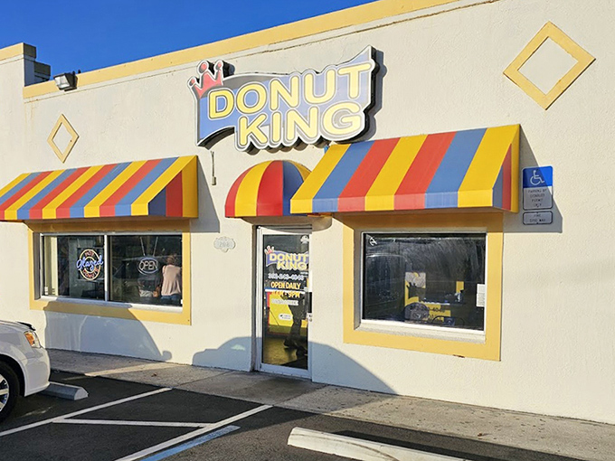 The cheerful yellow facade of Donut King with its rainbow-striped awnings beckons like a sugary oasis in Minneola.