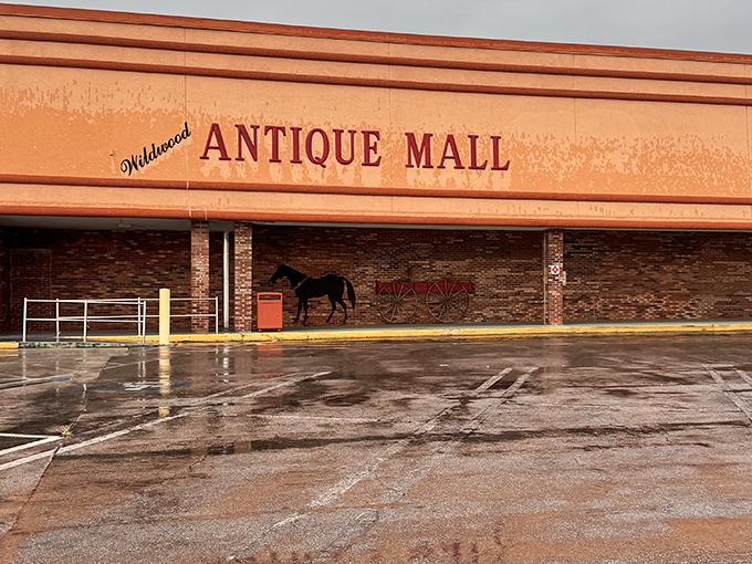 The peachy facade of Wildwood Antique Mall stands like a time portal on the roadside, its horse and wagon silhouette promising adventures in yesteryear.