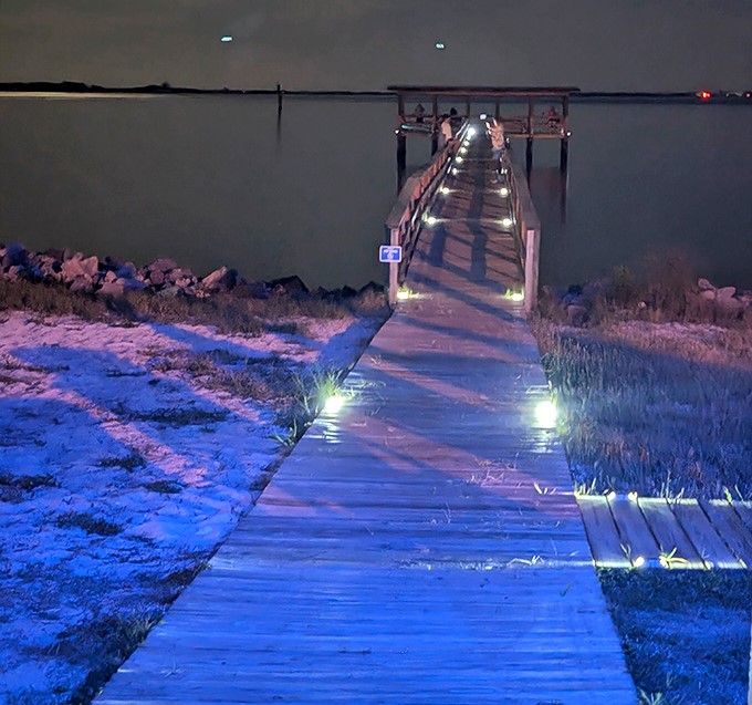 The pier at night becomes a magical walkway of lights, guiding evening strollers over waters that whisper vacation secrets.