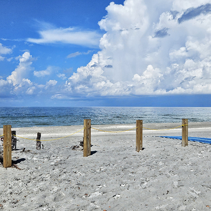 Blue sky shot at the beach: Where clouds perform their daily ballet above waters so clear you can count fish from the shore.