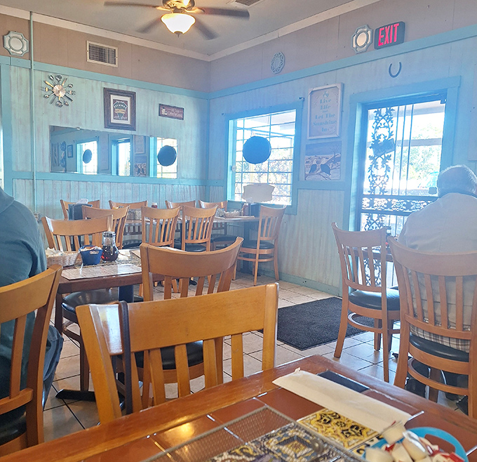 Sunlight streams through windows, illuminating the simple charm of wooden chairs and blue walls. A space designed for lingering conversations and second cups of coffee.