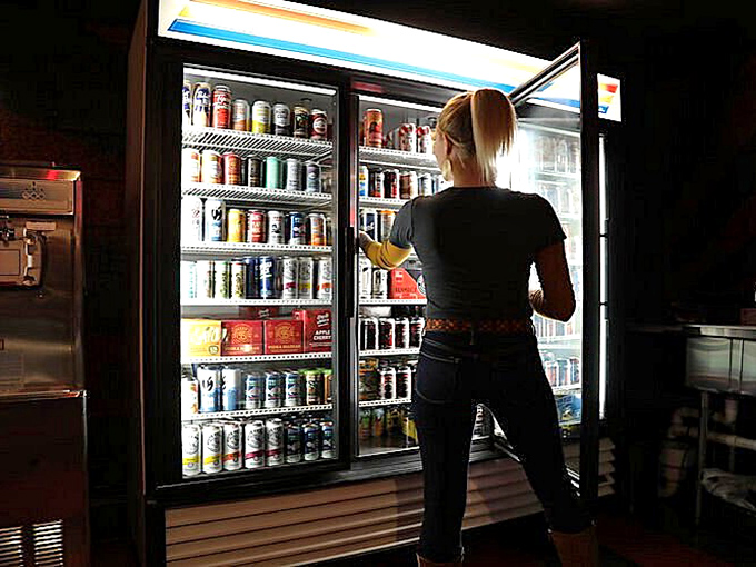 The illuminated beer fridge glows like a checkpoint beacon, offering liquid refreshment between intense rounds of digital combat.