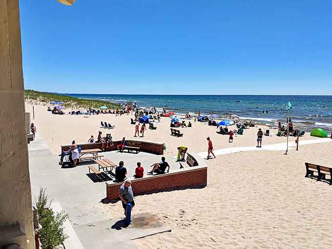 Beach-goers create a colorful mosaic against golden sands, each umbrella marking a temporary summer home.