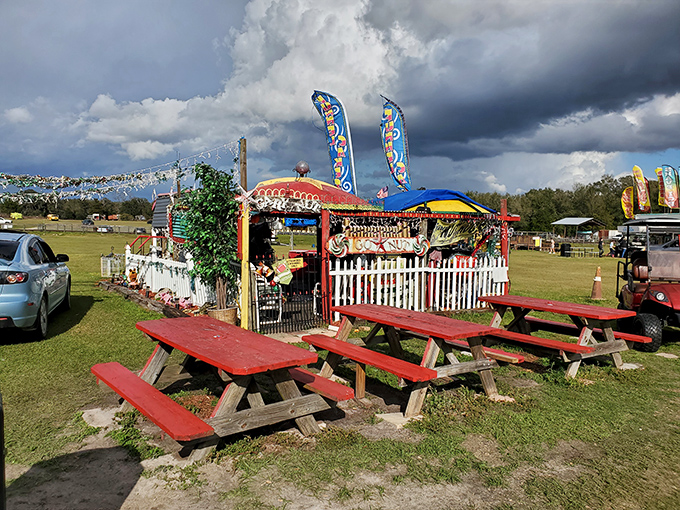 Picnic tables await hungry visitors outside a colorful food stall, where memories are made between bites of classic fair treats.