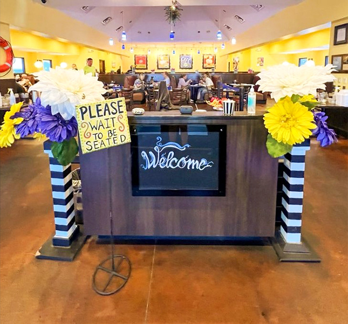 The host stand welcomes guests with cheerful flowers and a friendly "Please Wait to be Seated" sign&mdash;worth every minute.