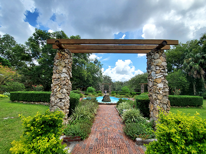 Stone pillars support wooden beams in this pergola, creating dappled shade for visitors while framing views of the meticulously maintained gardens.