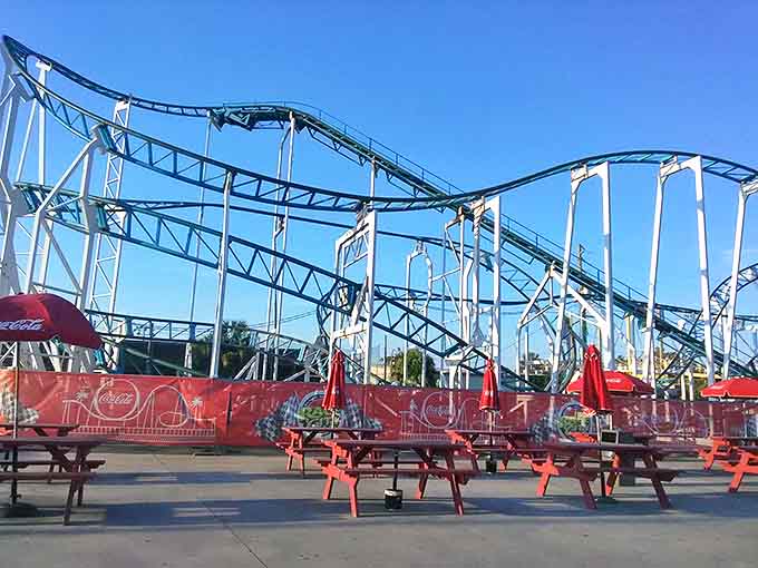 Red picnic tables stand ready for families to debate the age-old question: roller coaster first, or nachos first?
