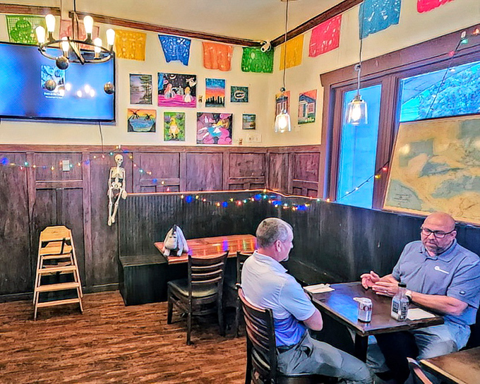 Colorful papel picado banners and warm wood paneling create a welcoming vibe where strangers become friends over shared food recommendations.