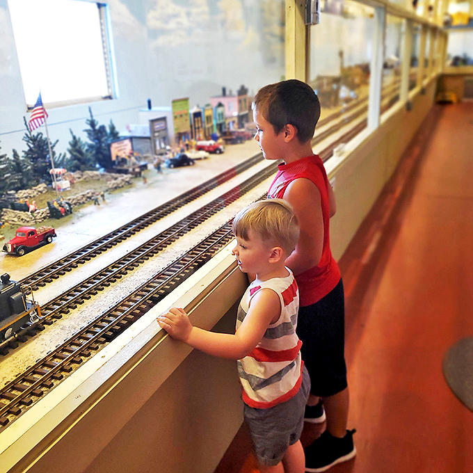 Kids inside the museum: Young explorers press against glass barriers, their fascination with miniature train worlds proving that some kinds of magic never need batteries.