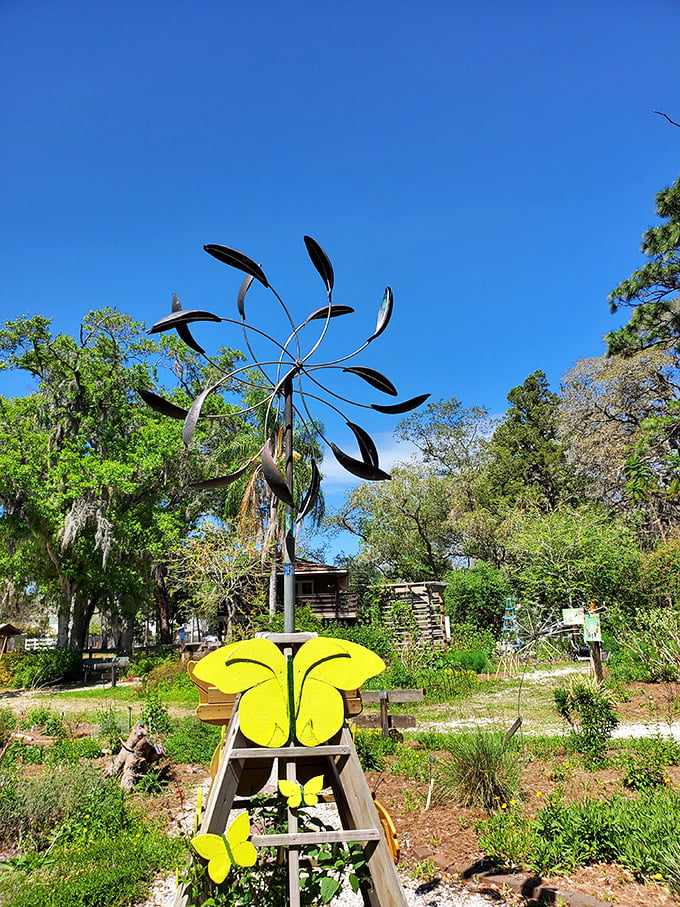 A metal wind sculpture catches Florida breezes against a perfect blue sky, with butterfly decorations adding whimsical touches below.