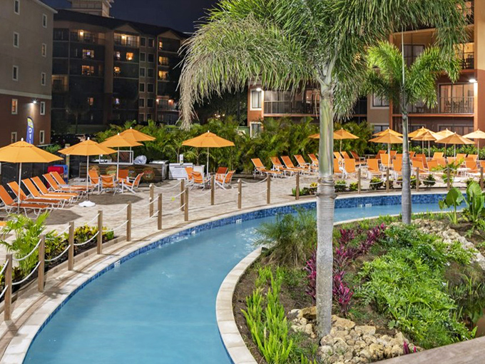 Evening transforms the pool area into a tranquil retreat, where the day's excitement mellows into peaceful reflection under palm trees.