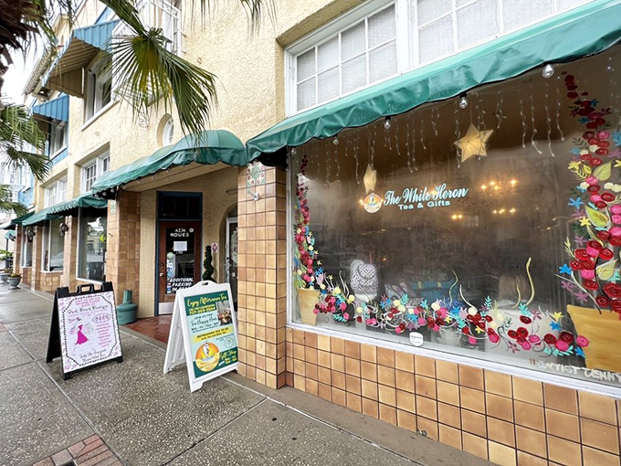 The White Heron's charming storefront with green awning and festive window displays calls to tea lovers like a lighthouse beacon.