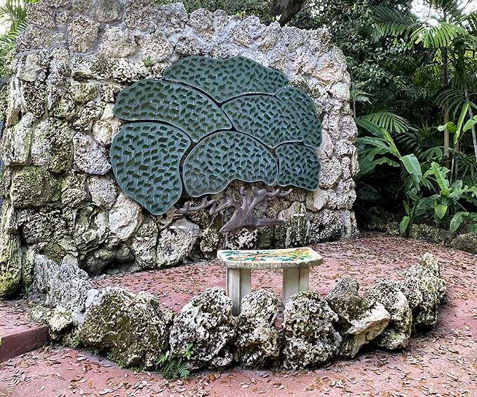 This verdant metal tree sculpture seems to grow from the rock wall itself, its artistic interpretation of nature complementing the real plants surrounding it.