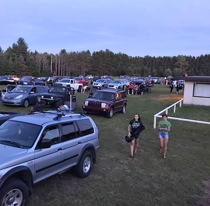 Cars arrange themselves in neat rows like eager students, each with perfect attendance for tonight's lesson in escapism.