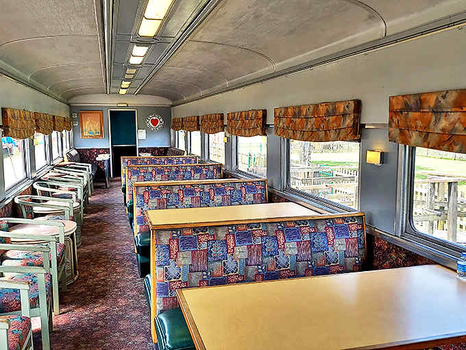 The dining car interior invites passengers to imagine elegant meals served while countryside views rolled past these very windows.