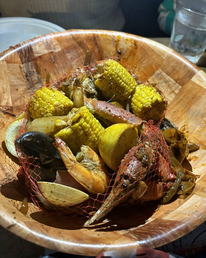 The seafood boil arrives like buried treasure in a wooden bowl &ndash; corn, potatoes, and shellfish swimming in spices that would make Neptune himself salivate.