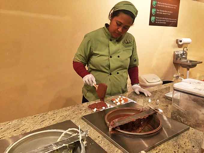 A skilled chocolatier demonstrates her craft, transforming liquid chocolate into solid joy with practiced precision and a steady hand.