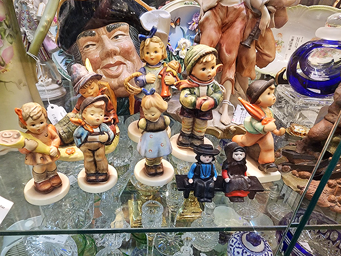 Hummel figurines and delicate glassware share space in this gleaming display case, their pristine condition a testament to generations of careful ownership.