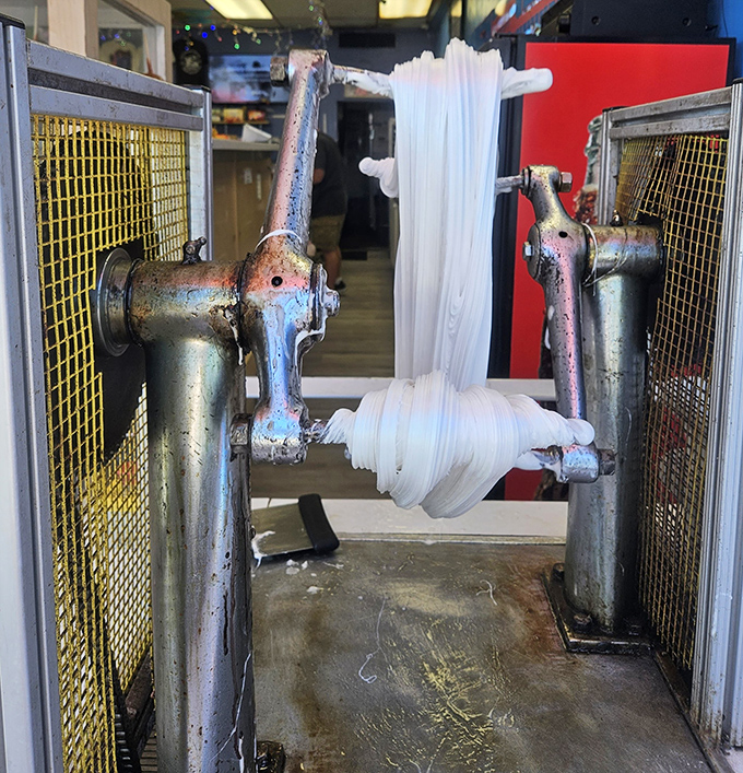 The vintage taffy-pulling machine, a mechanical marvel that transforms sugar into stretchy, chewy perfection before your eyes.