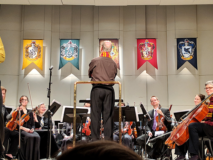Harry Potter house banners hang above musicians, proving even wizarding schools appreciate the acoustics of historic theaters.