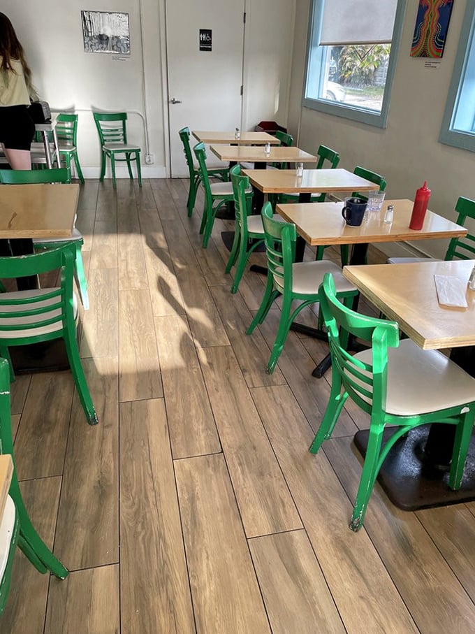 Bright green chairs pop against wooden tables in this cozy space where strangers become friends over shared food revelations.