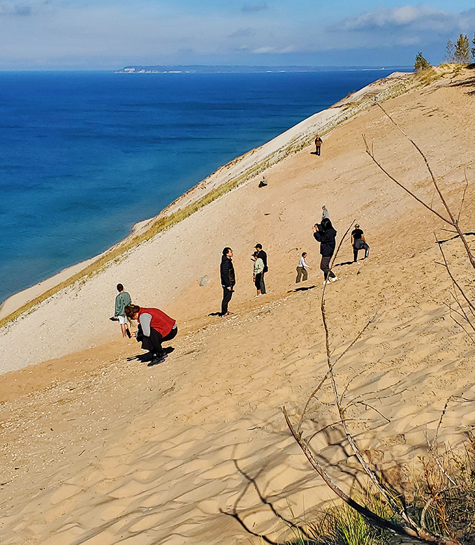 Visitors brave the steep dune descent, blissfully unaware of the quad-burning climb that awaits their return journey.