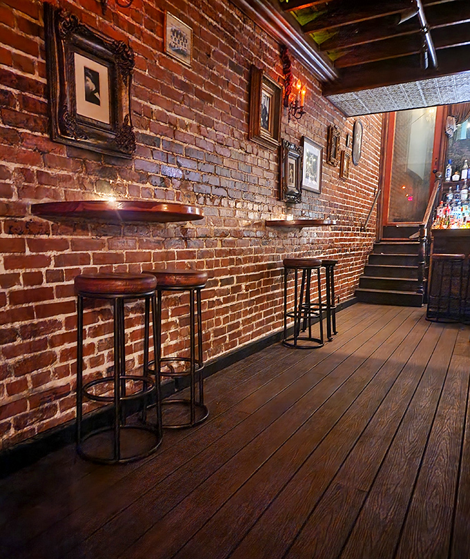 Wooden stools await conspirators along brick walls adorned with vintage frames &ndash; perfect for plotting your next great adventure.