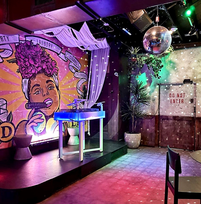 A vibrant mural watches over the performance space where a disco ball scatters light like stars across this hidden Havana-inspired paradise.