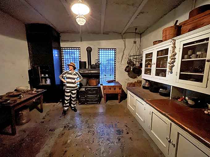 The prison kitchen stands frozen in time, with its vintage stove and simple furnishings revealing the institutional approach to feeding inmates.