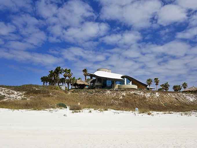 A modern architectural marvel perches dramatically on the dunes, its curved roofline echoing the waves it overlooks.