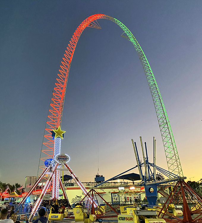 The SkyCoaster arcs against the sunset like a neon rainbow, promising riders the closest thing to human flight without actual wings.