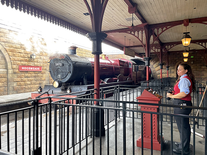 A station attendant stands ready at her post, maintaining the immersive illusion that you're truly departing for a magical destination.