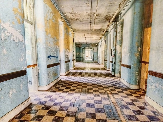 Peeling paint and checkerboard floors create an eerie beauty in this abandoned ward hallway, where time seems frozen between past and present.