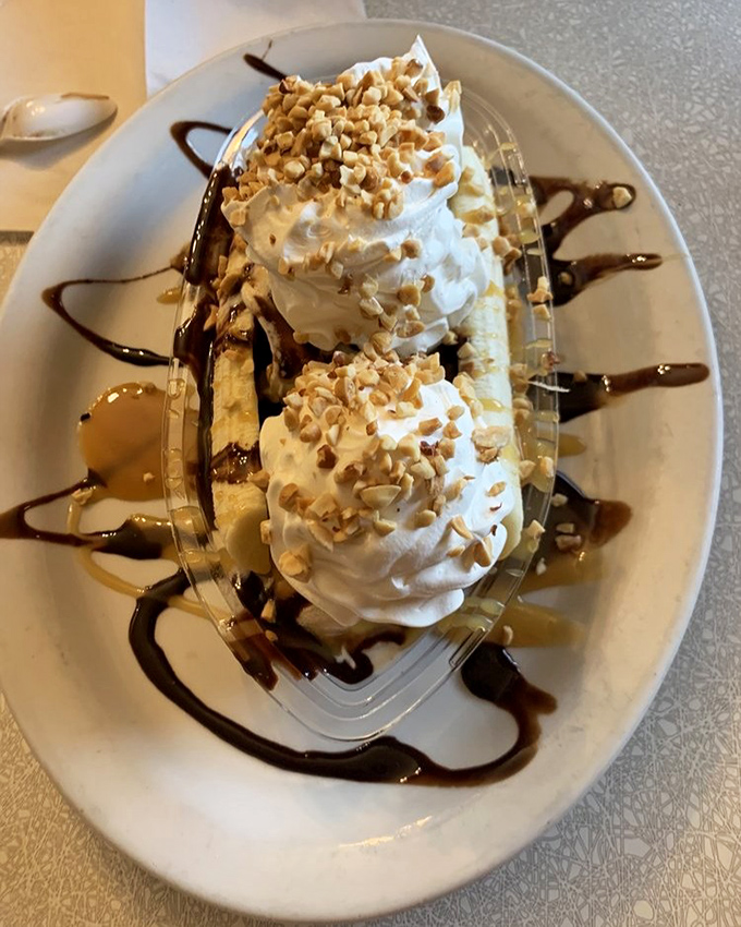 This banana split isn't dessert&mdash;it's architecture. Whipped cream towers, chocolate drizzle, and enough nuts to make a squirrel jealous, all in a classic boat dish.